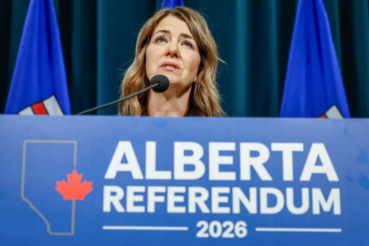 Photo of Alberta premier Danielle Smith behind a blue podium with a ...