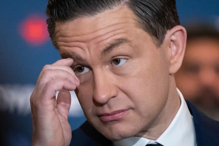 A closeup photo of Pierre Poilievre, wearing a suit and tie, his hand ...