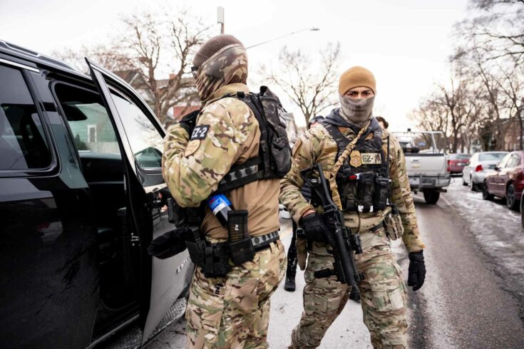 Image of two federal ICE agents wearing camouflage clothes and vests.