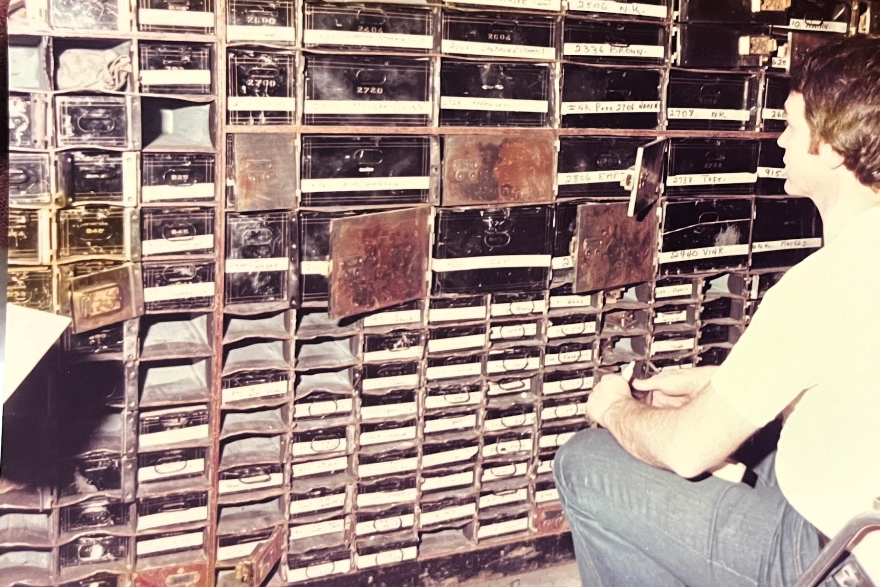 Photo of a person sitting in a chair in front of a wall of open safe ...