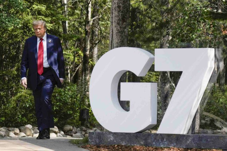 Photo shows US president Donald Trump walking past a "G7" sign
