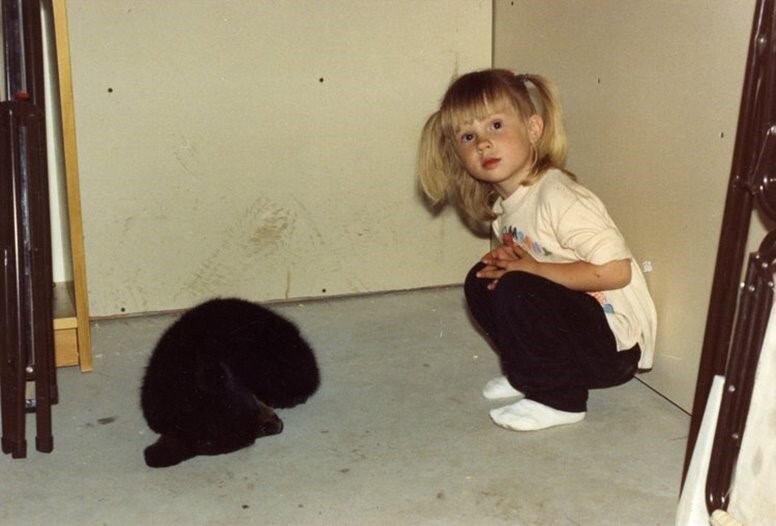 Photograph of a blonde child with pigtails crouching next to a black ...