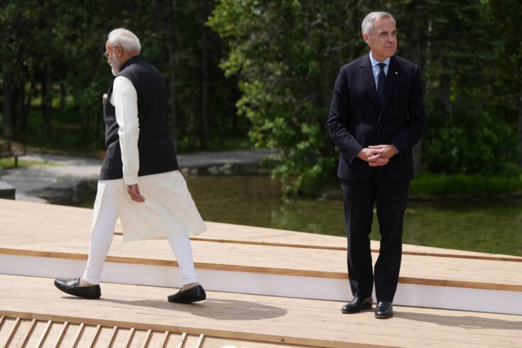 Narendra Modi walks away from Mark Carney, who has his hands folded ...
